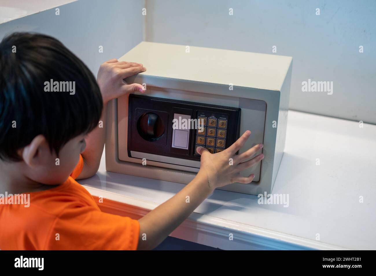 Little Asian boy opening safe at home Stock Photo - Alamy