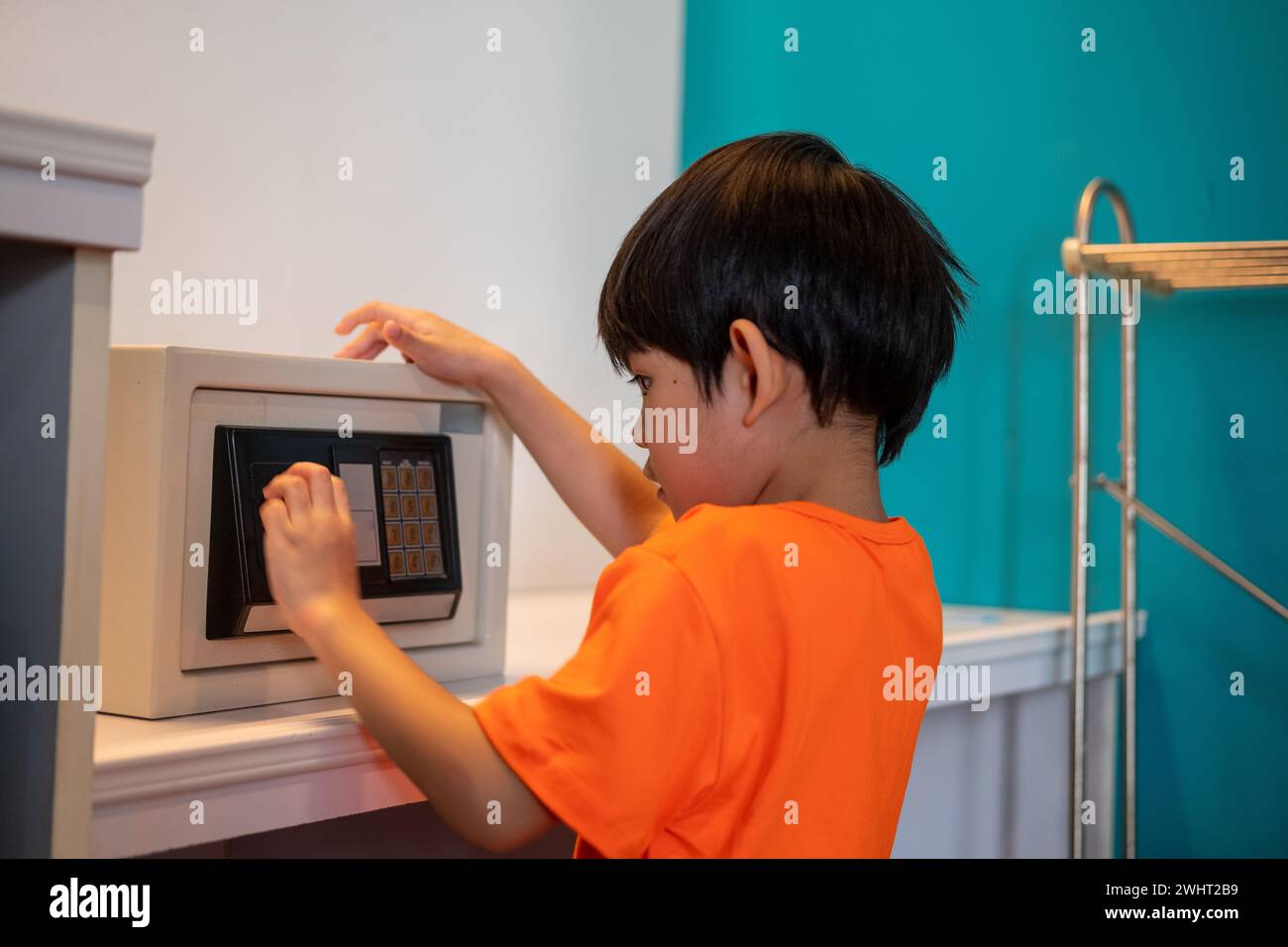 Little Asian boy opening safe at home Stock Photo - Alamy