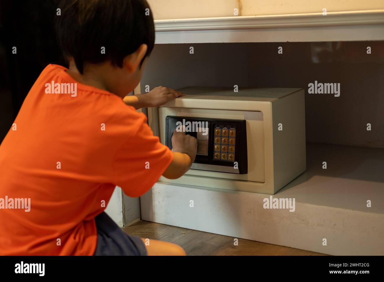 Little Asian boy opening safe at home Stock Photo - Alamy