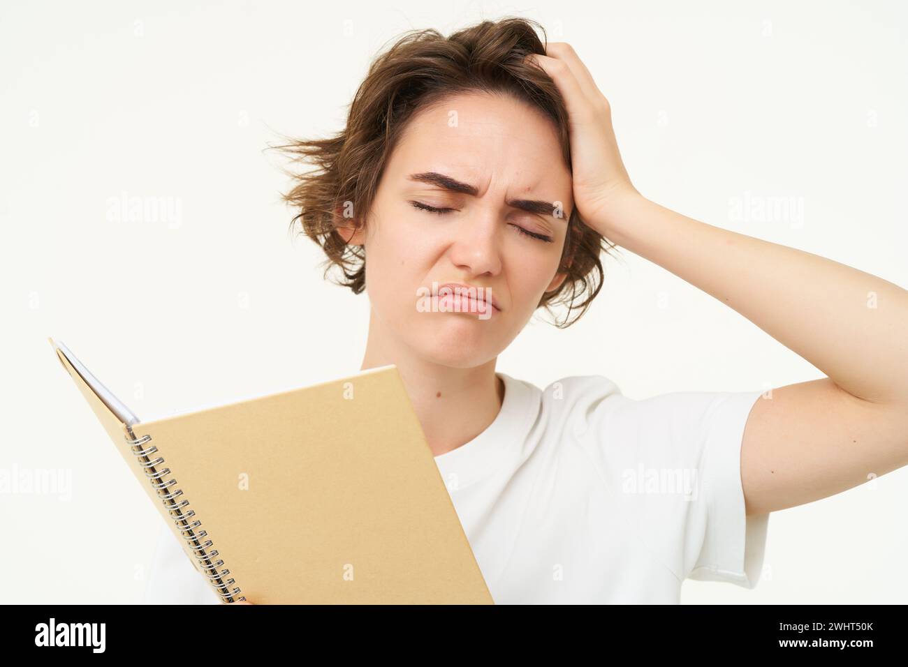 Portrait of puzzled, upset young woman tired of doing homework, holding ...