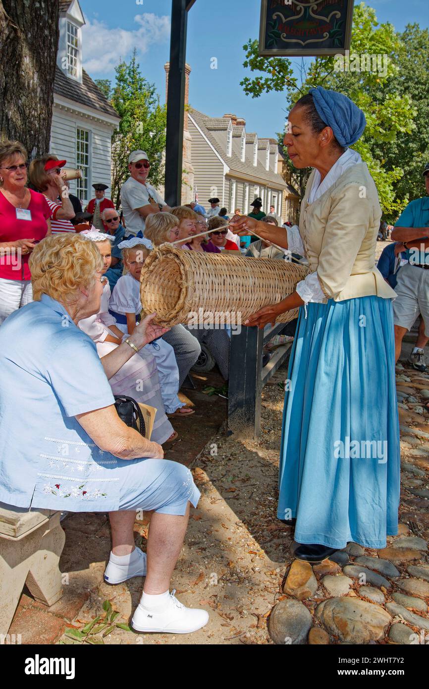 female interpreter, black woman, in period dress, shows woven basket to ...