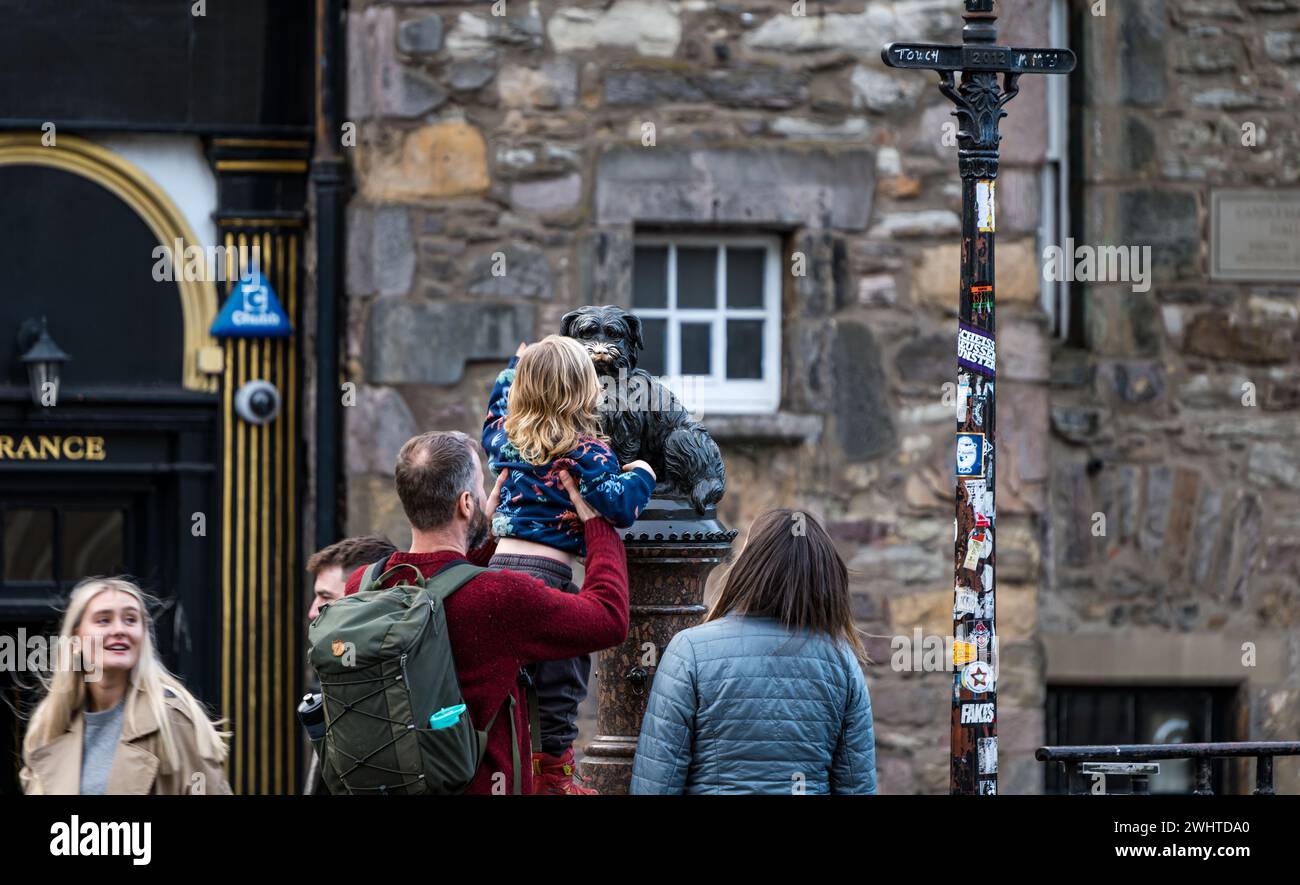 Tourist touching nose of Greyfriar's Bobby dog statue for good luck ...