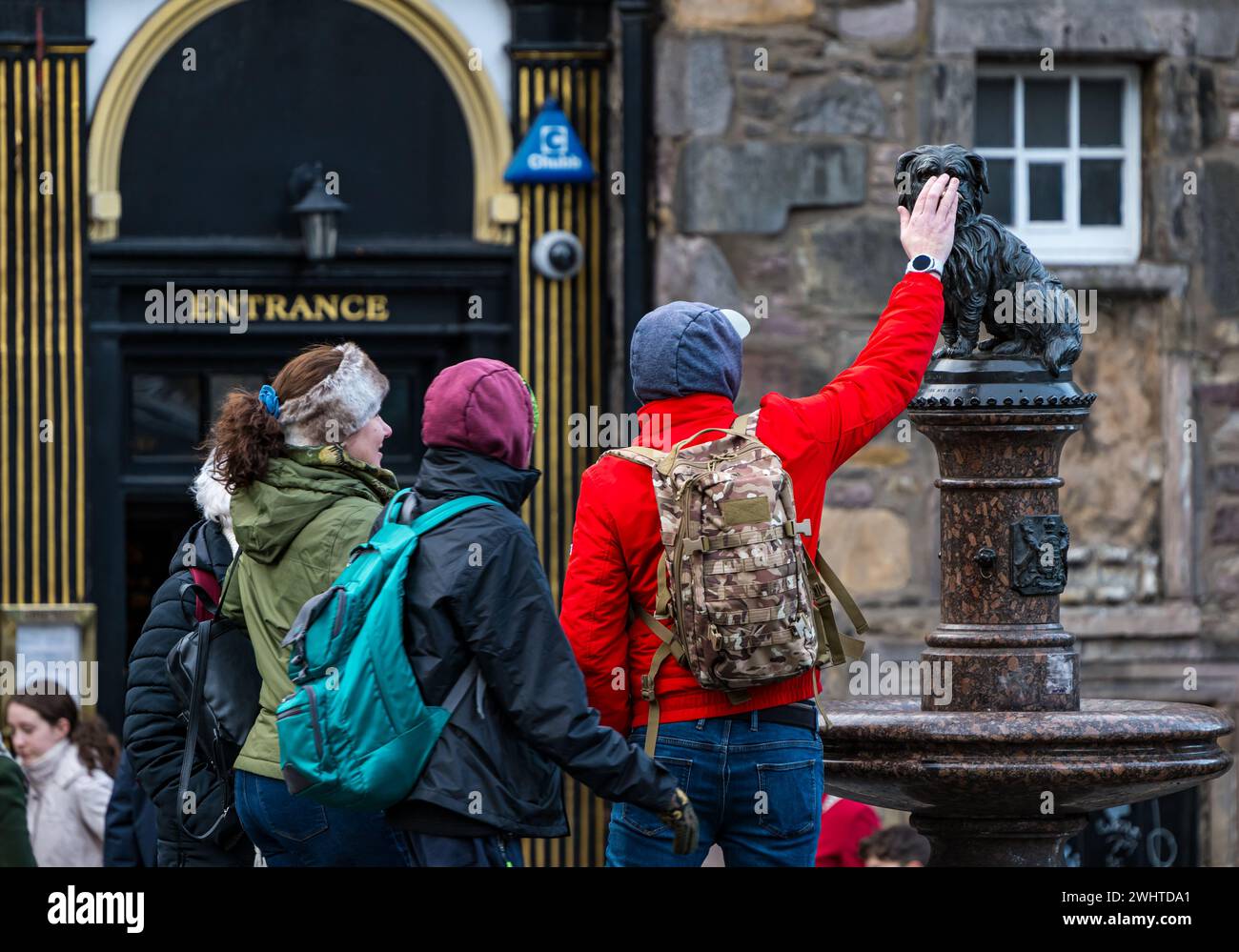 Tourist touching nose of Greyfriar's Bobby dog statue for good luck ...