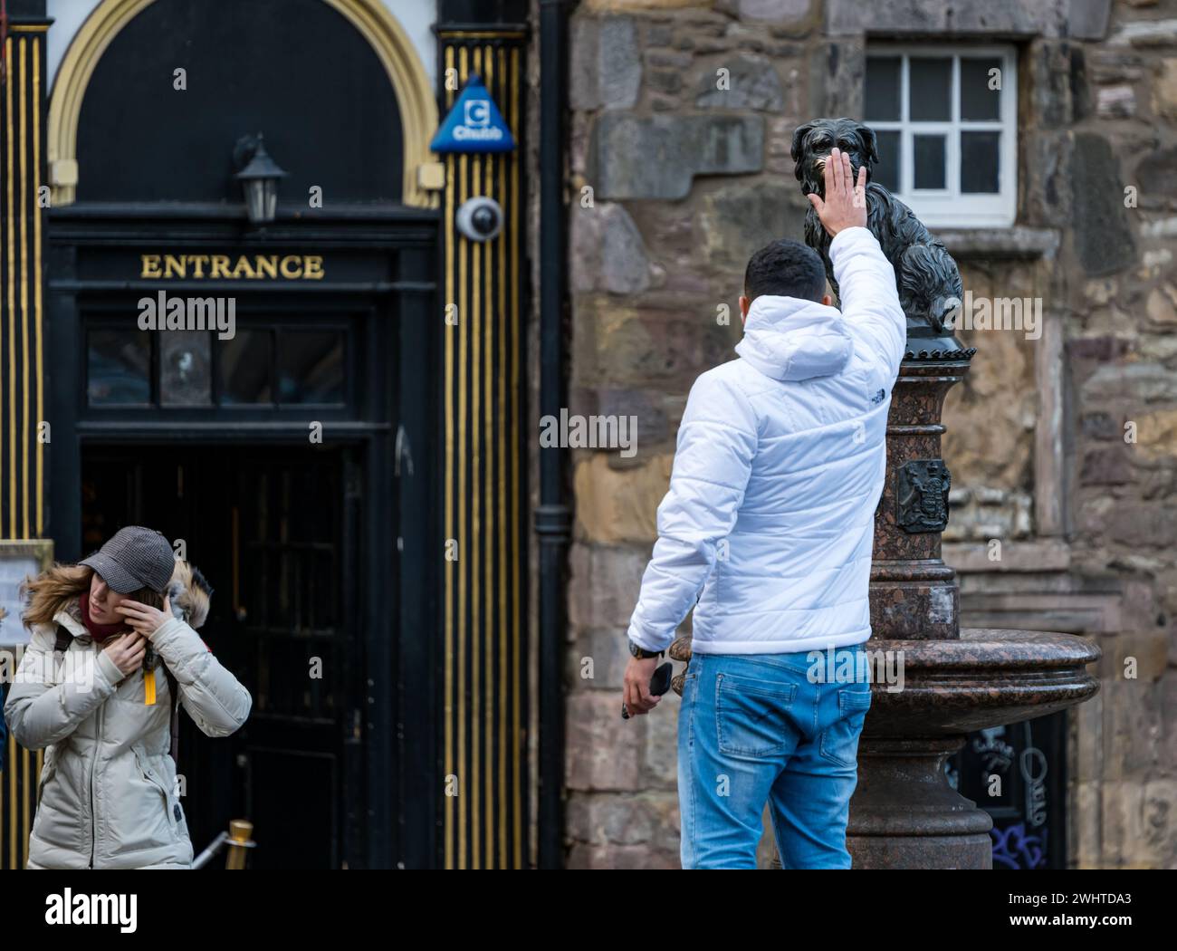 Tourist touching nose of Greyfriar's Bobby dog statue for good luck ...