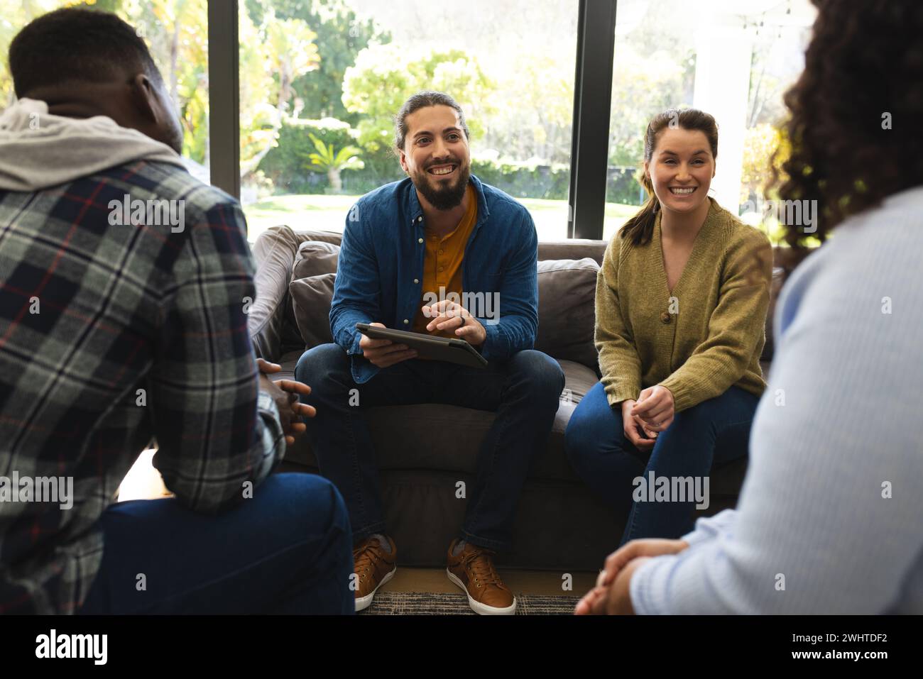 Diverse group of friends and male therapist with tablet in group ...