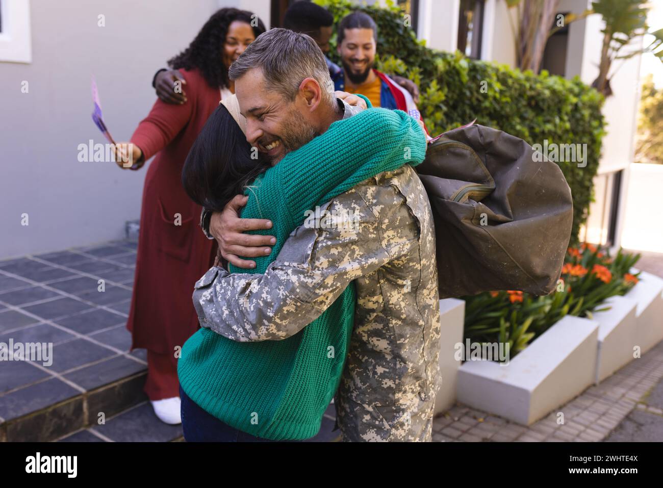 Happy diverse friends with flags welcoming home male soldier friend ...