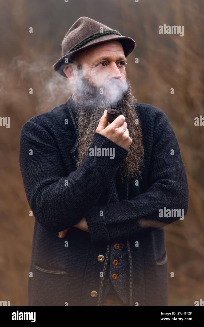 Portrait of a typical bavarian man smoking a pipe and wearing a ...