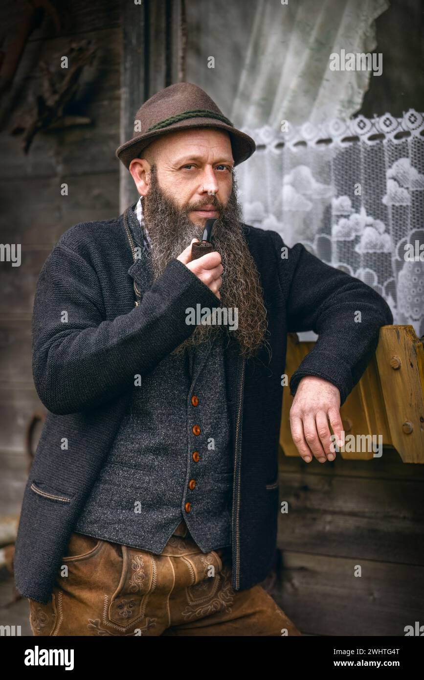 Portrait of a typical bavarian man smoking a pipe and wearing a ...