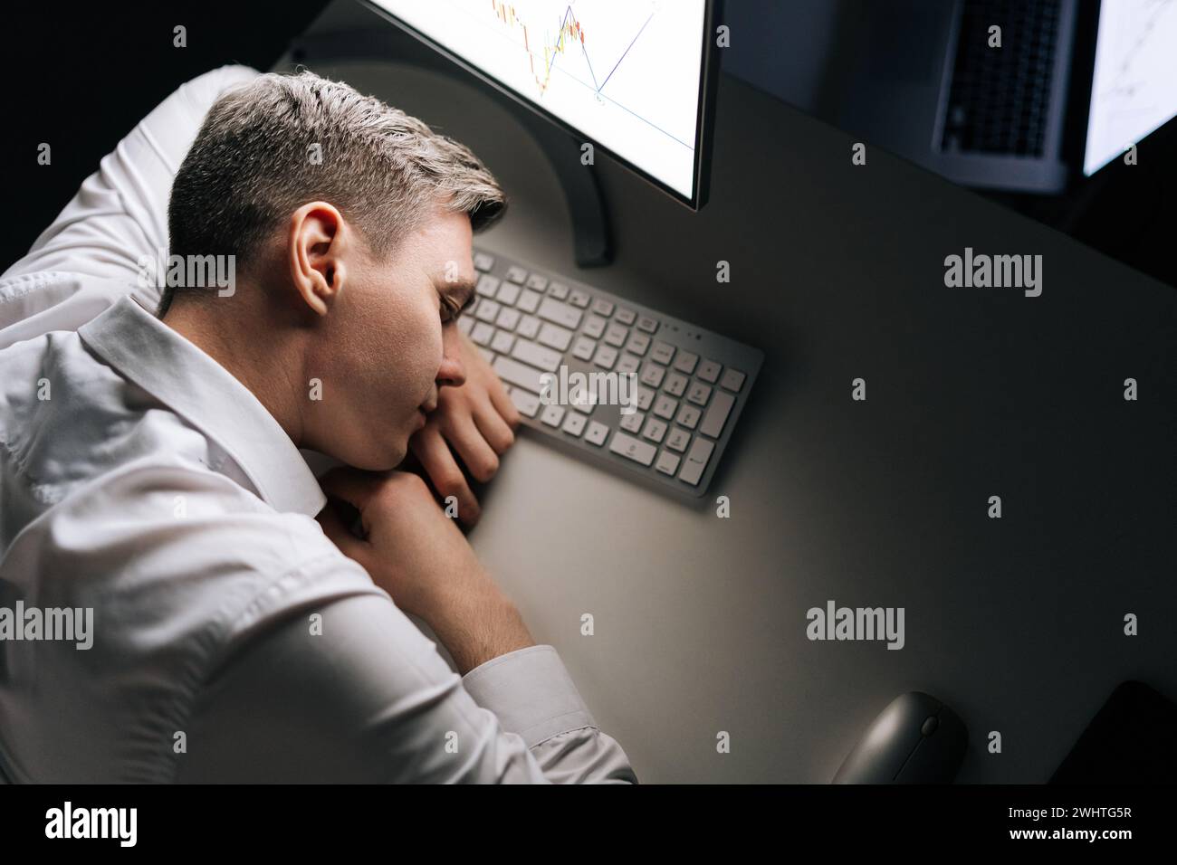 Top view of tired sleepy male employee asleep on computer desk late at ...