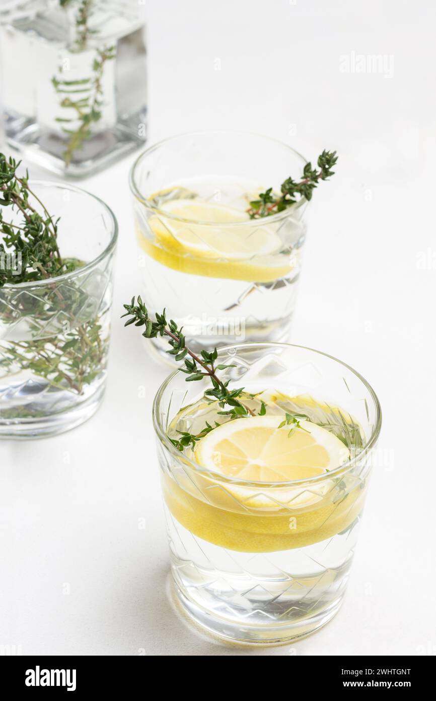 Glass with lemon and sprig of thyme. Lemon slice on table. White ...