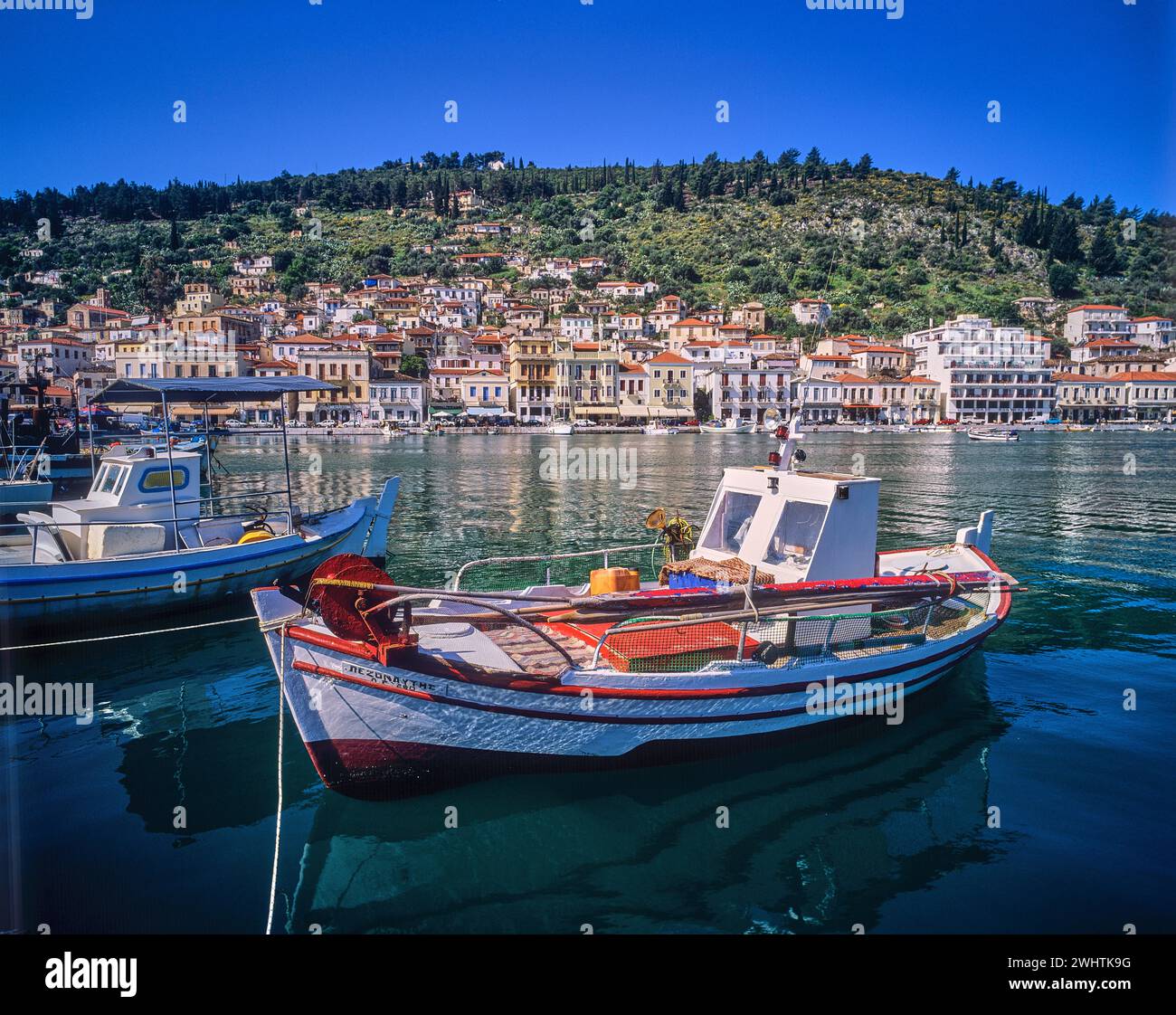 Small boats in the calm harbour water with mountain and city view in ...