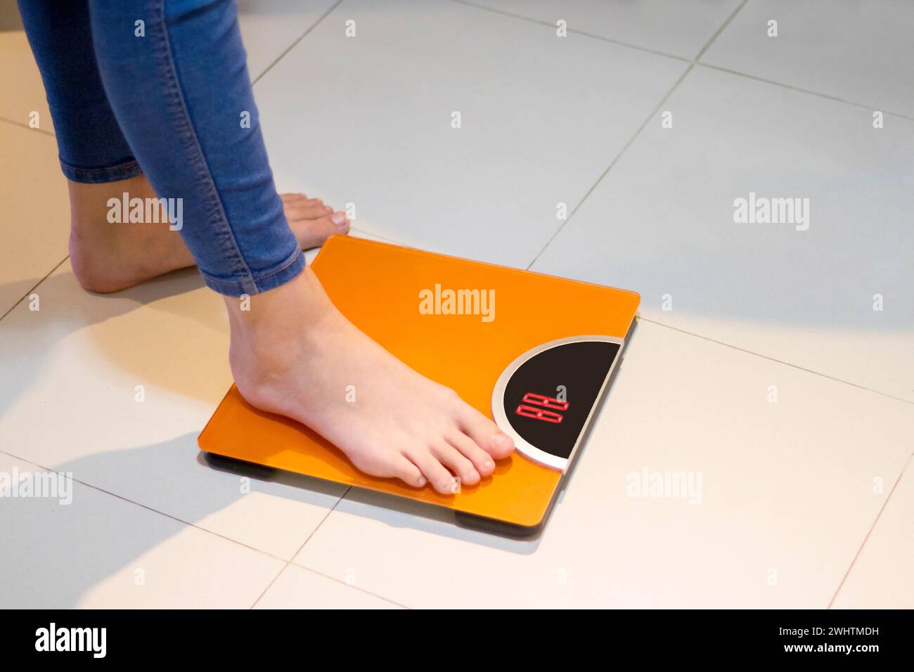 Woman's feet stepping onto a bathroom scale Stock Photo - Alamy