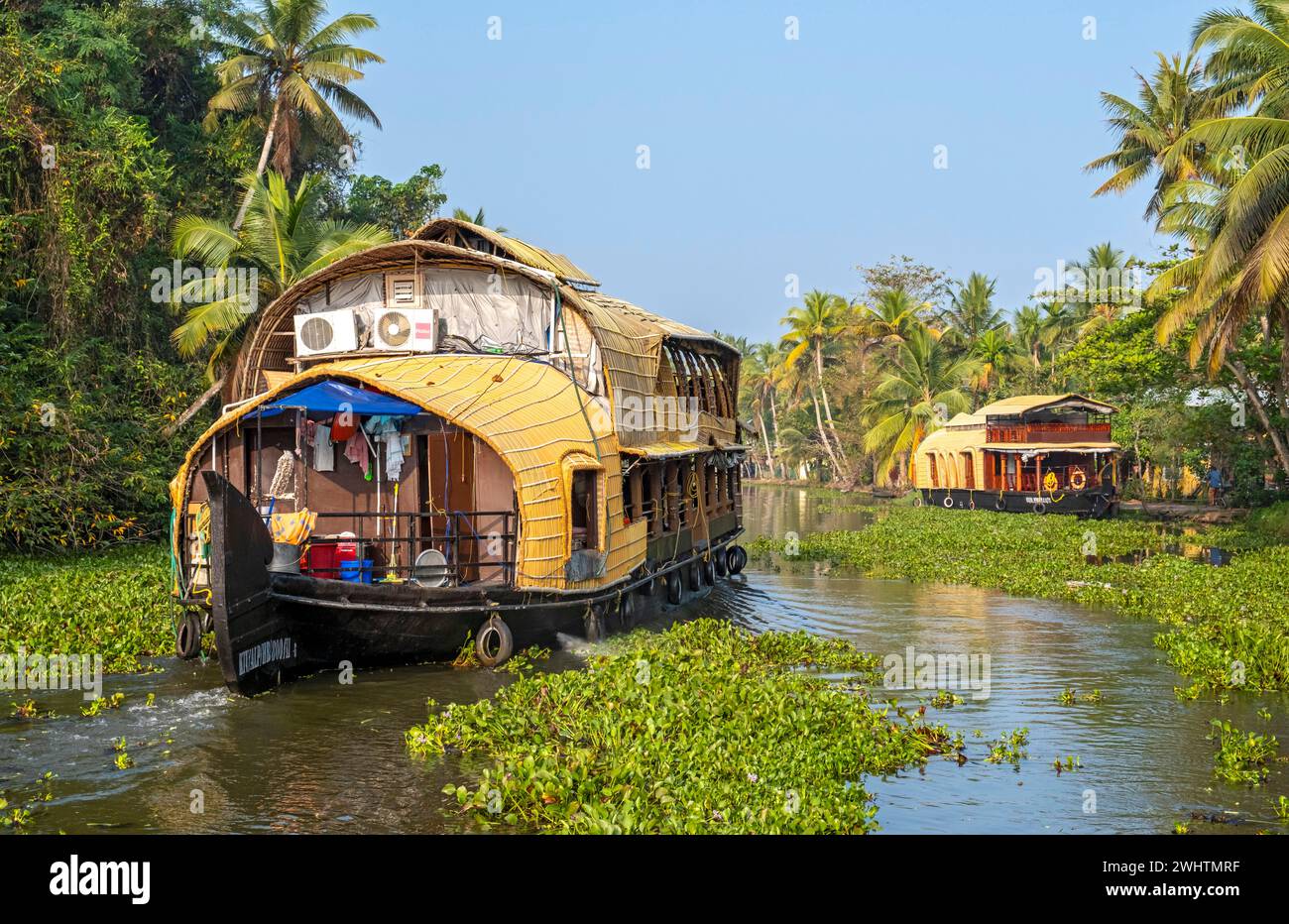 A traditional houseboat cruises along the channels near Kumarakom ...