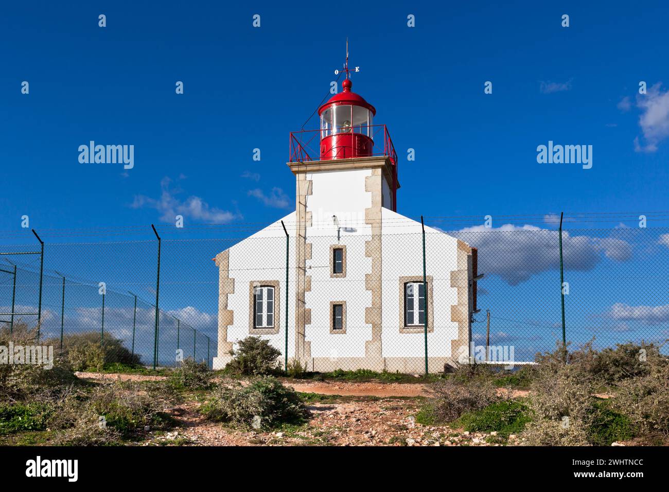 Bright Lighthouse beyond chain link fence Stock Photo - Alamy