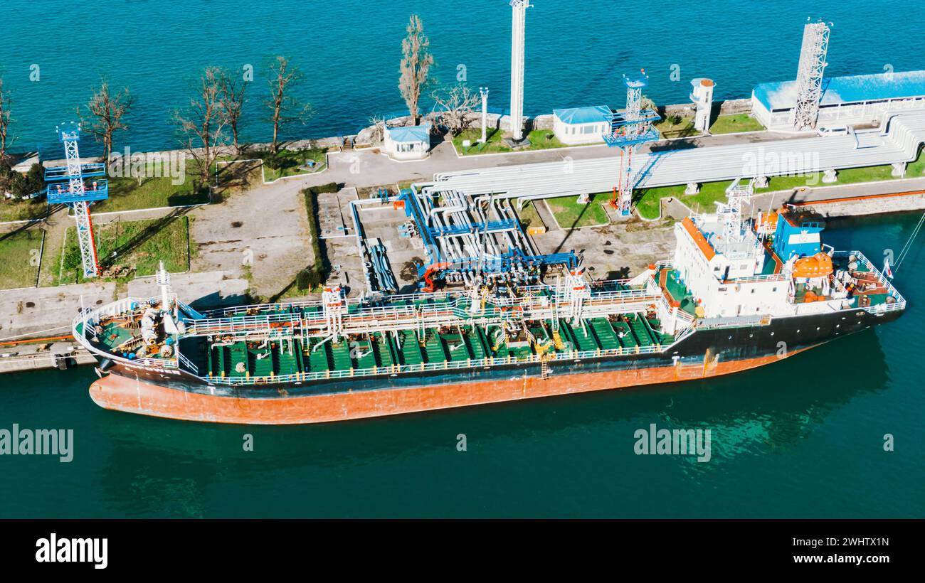 Aerial shot captures a large tanker ship moored at a port, surrounded ...