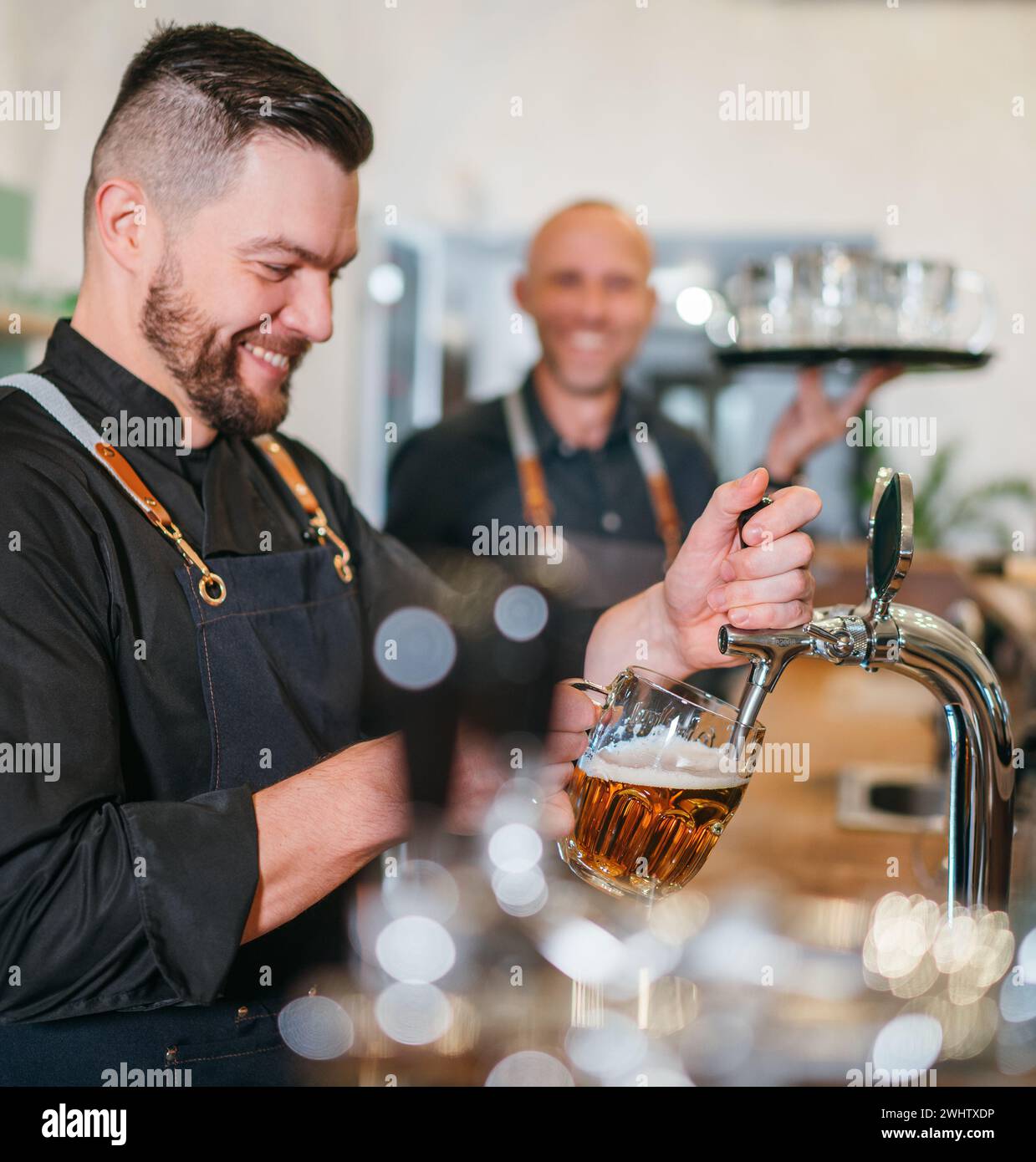 Stylish bearded barman dressed black uniform beer tapping at bar ...