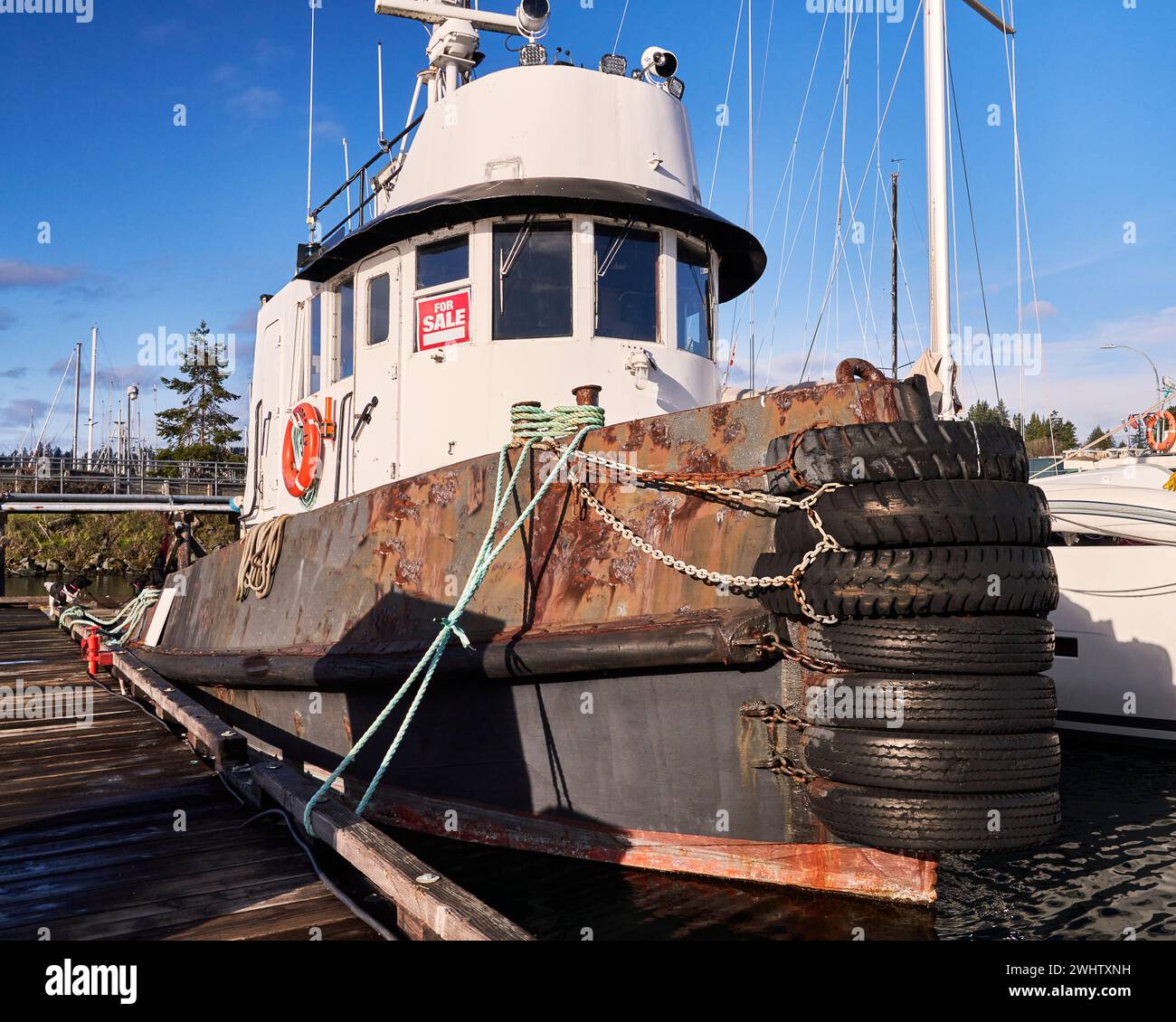 An old rusty tug with a for sale sign in the window. Tied up at a dock ...