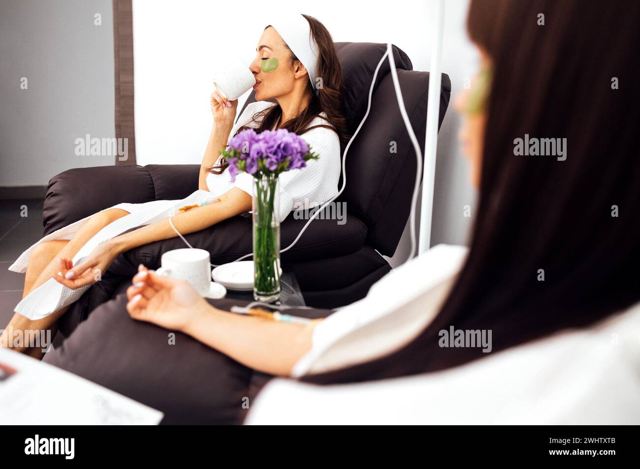 Two caucasian girls in bathrobes make wellness dropper with vitamins in ...