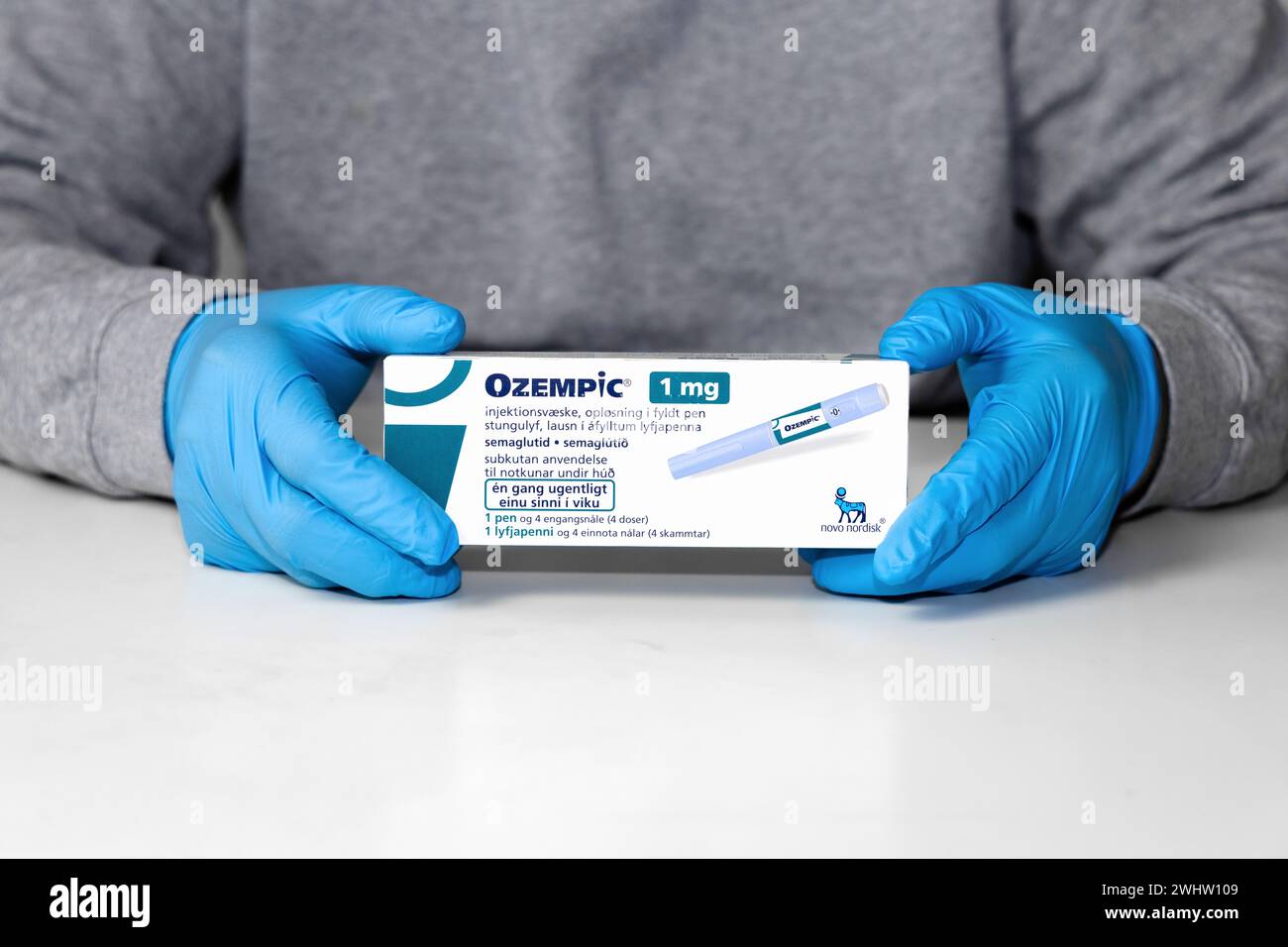 Hands in blue surgical gloves holding a package with Ozempic Insulin ...