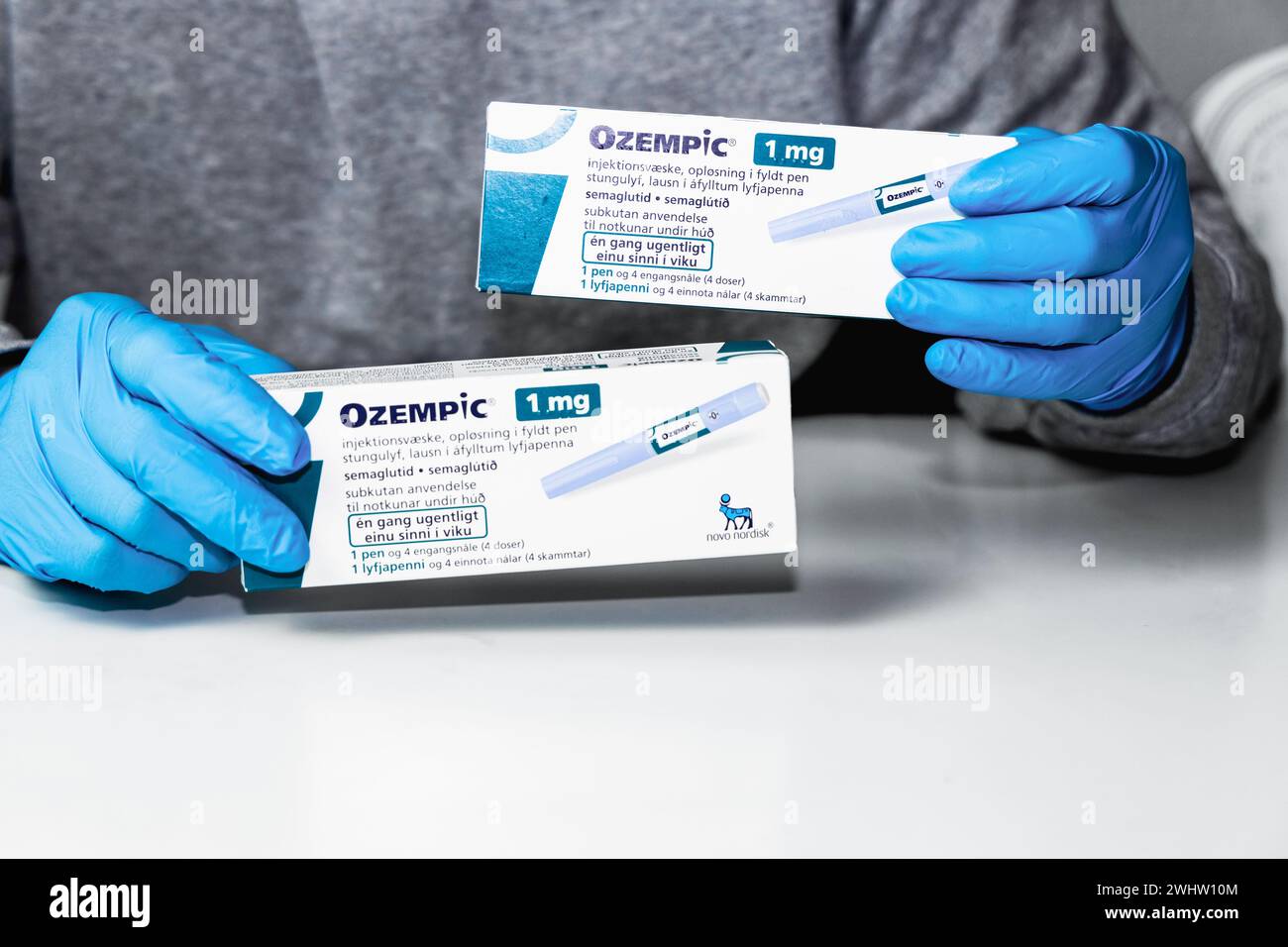 Hands in blue surgical gloves holding a package with Ozempic Insulin ...