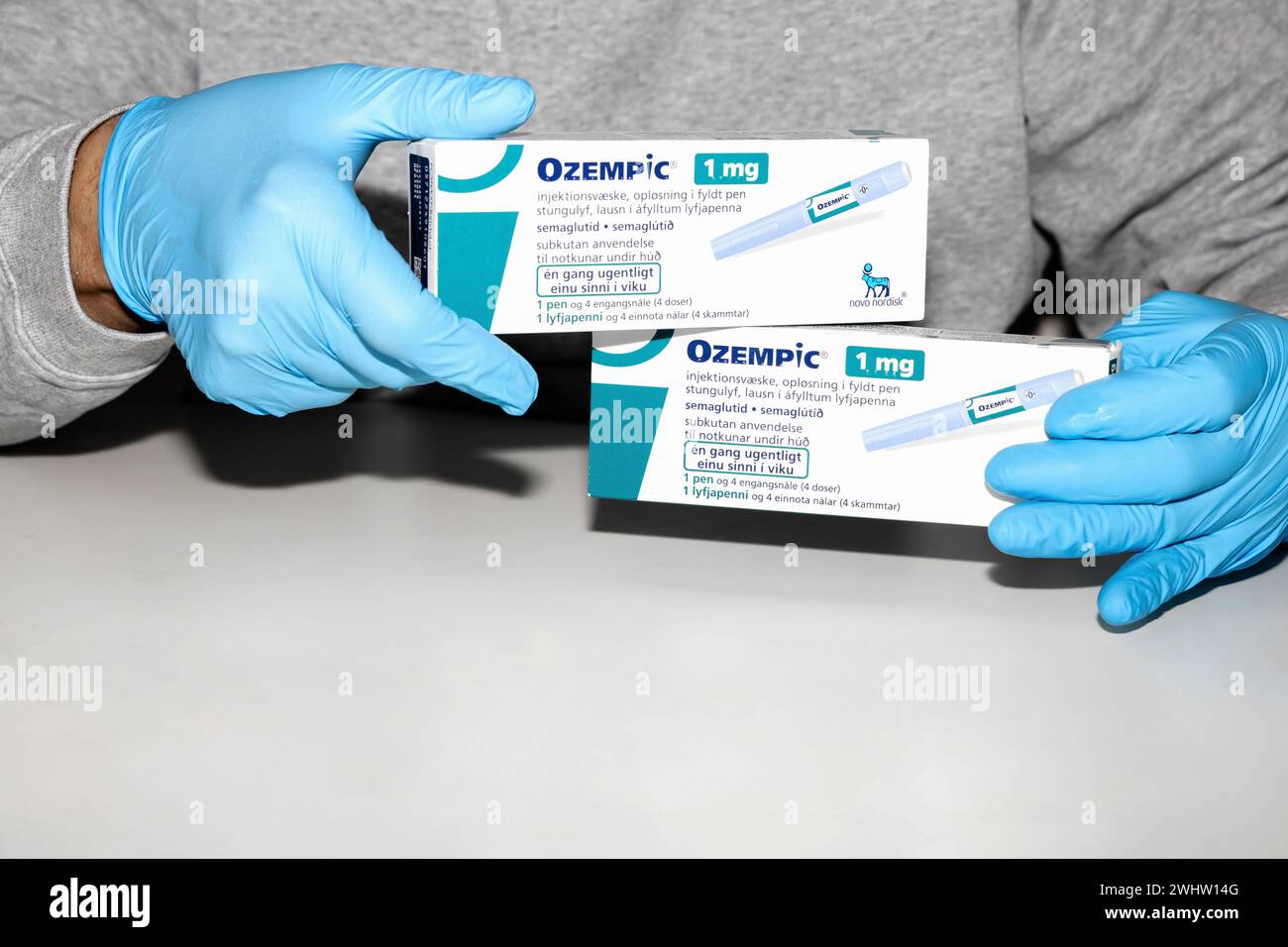 Hands in blue surgical gloves holding a package with Ozempic Insulin ...