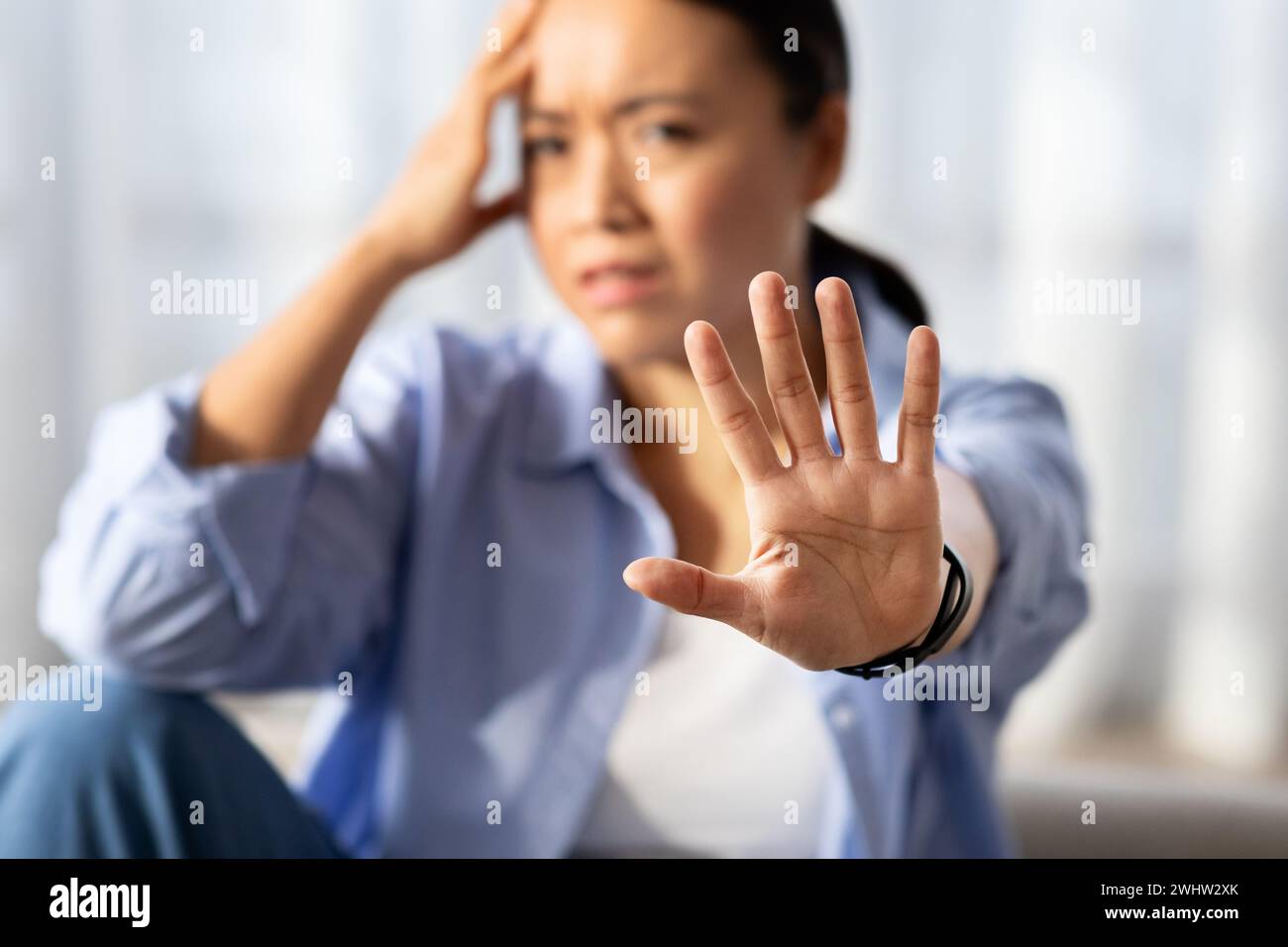 Asian woman showing stop gesture, home interior Stock Photo - Alamy