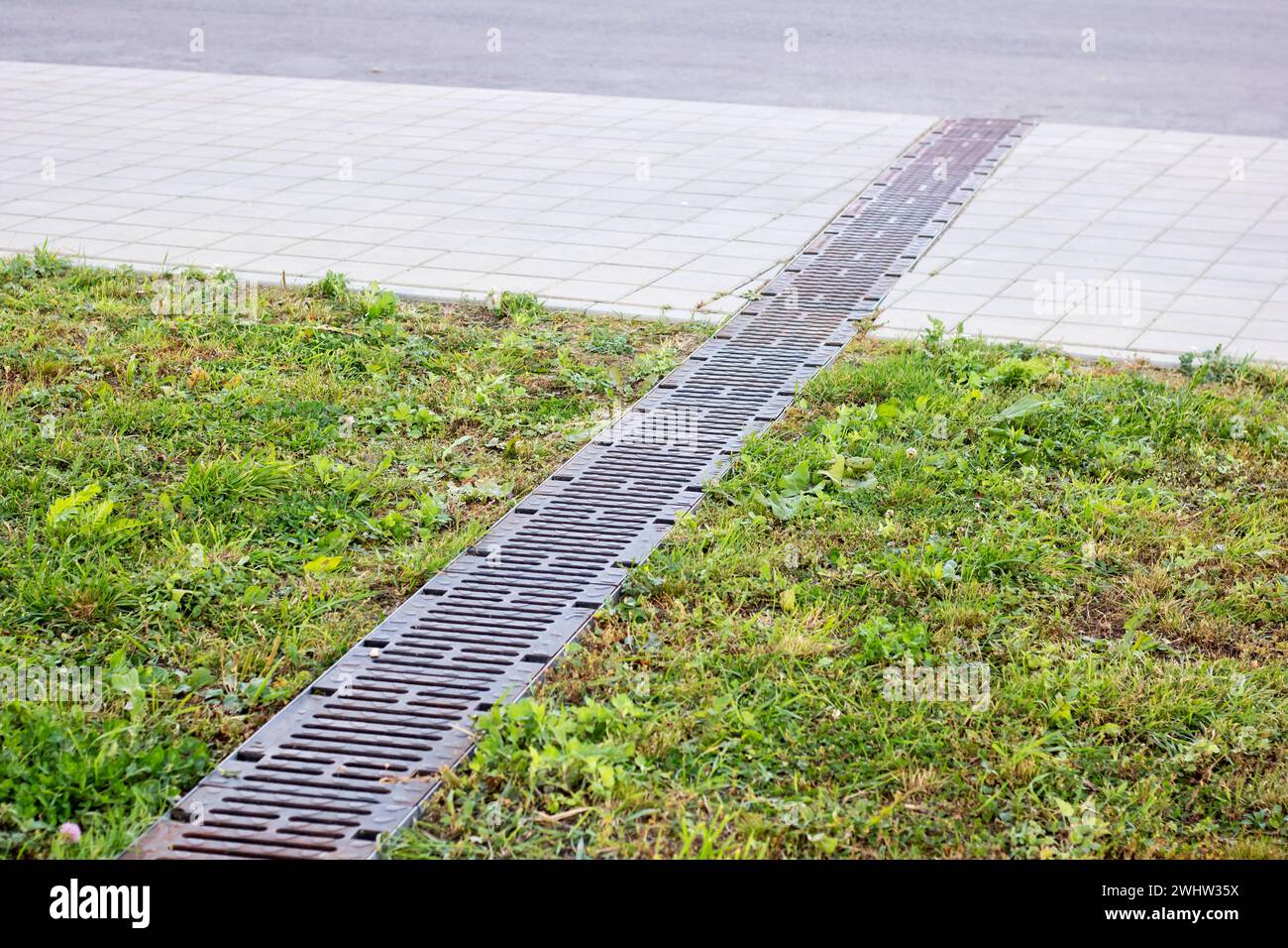 Long Rain drain on grass and pavement close up Stock Photo - Alamy