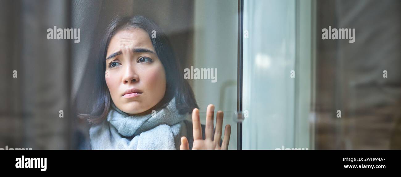 Vertical Shot Of Upset Asian Woman Looking Outside Touching Window