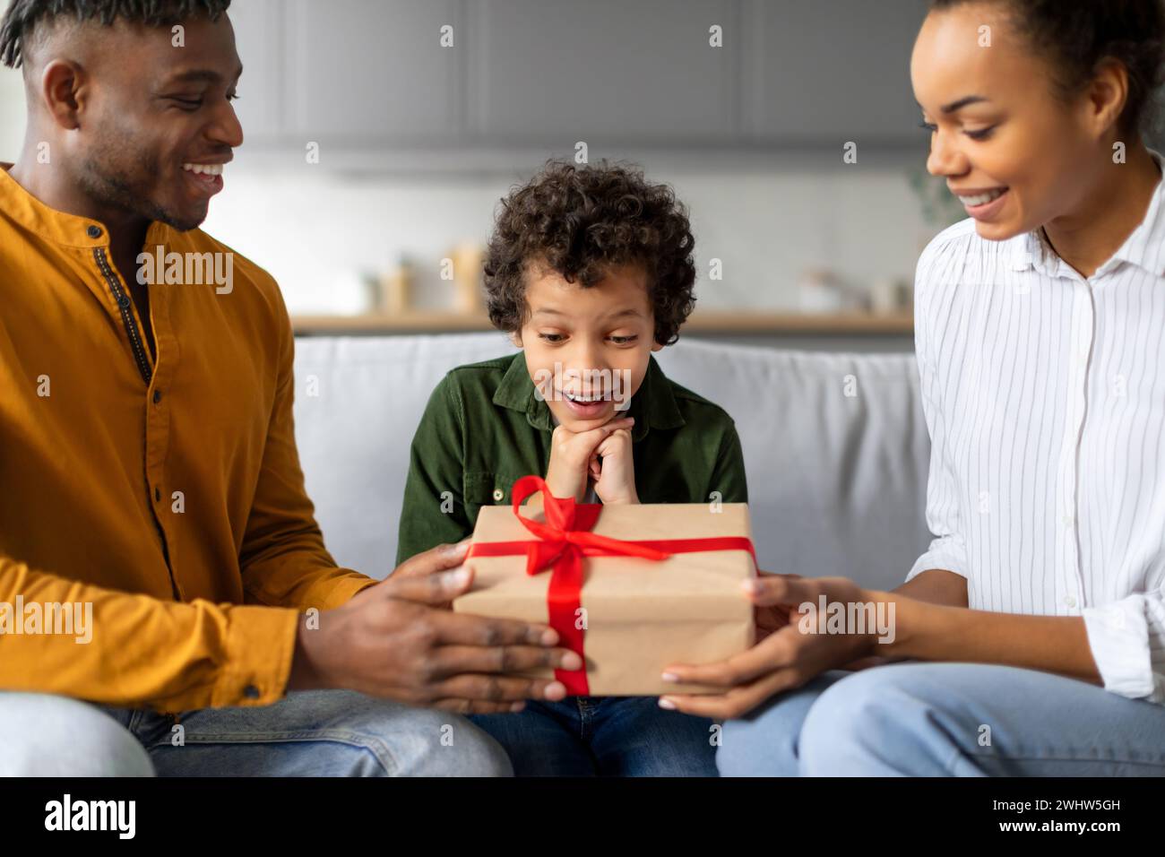Surprised child boy receiving gift from parents, happy family moment ...