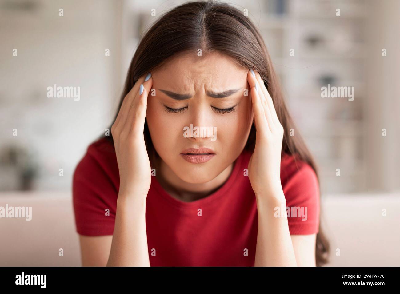 Distraught young asian woman with painful face expression holding her ...