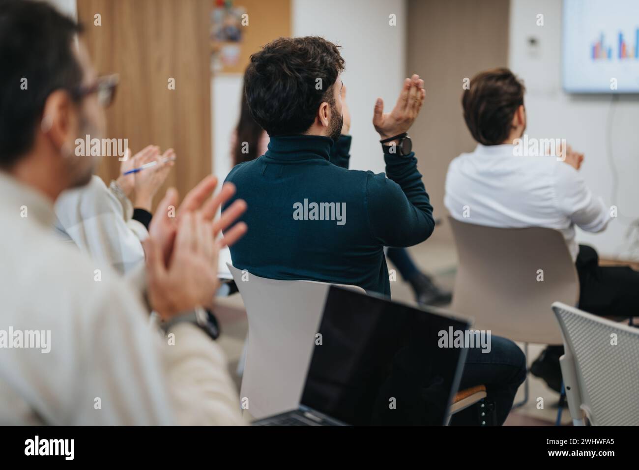 A group of business colleagues clapping in an office, showing ...