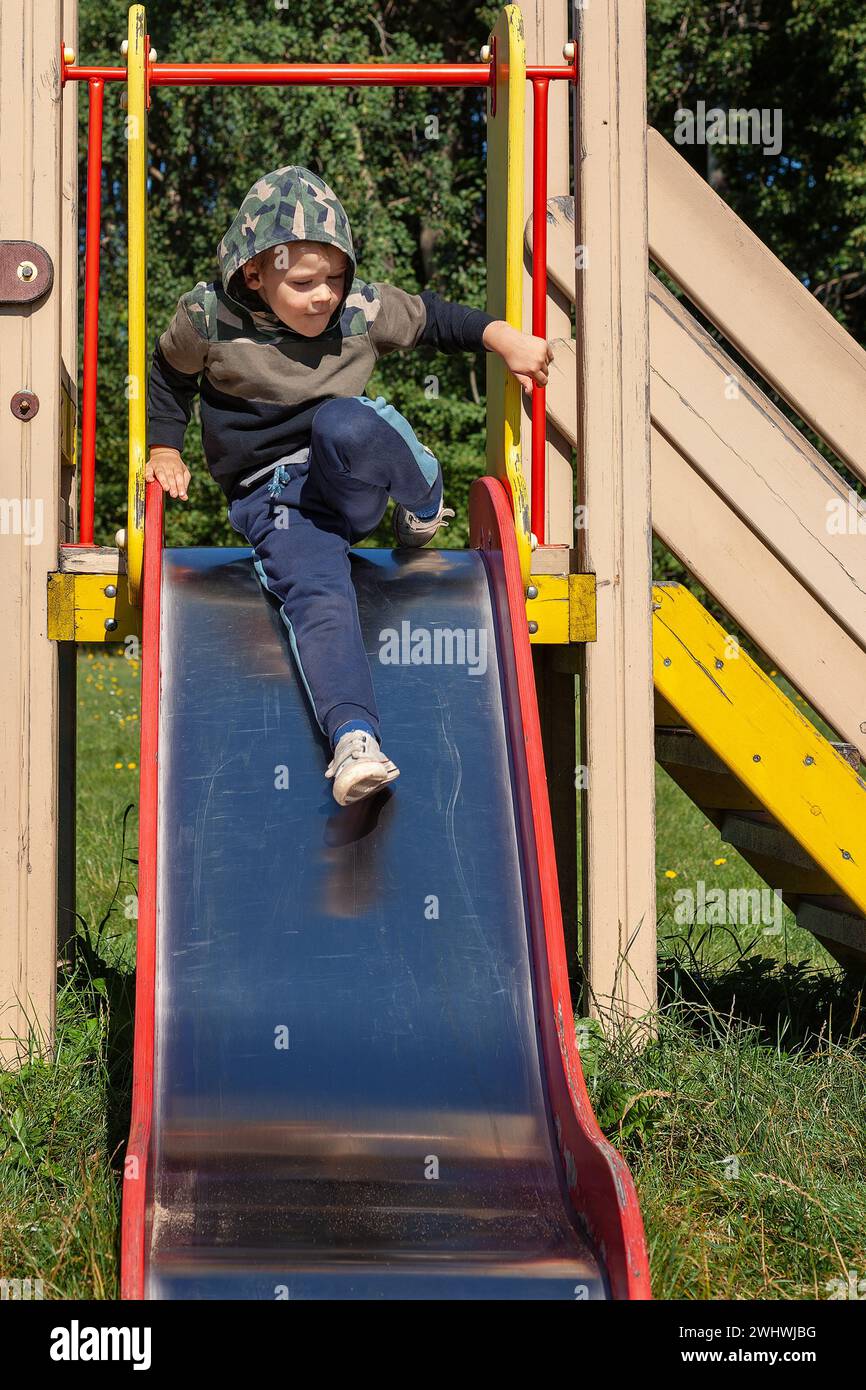 Happy kid boy having fun and sliding on outdoor playground. Child ...