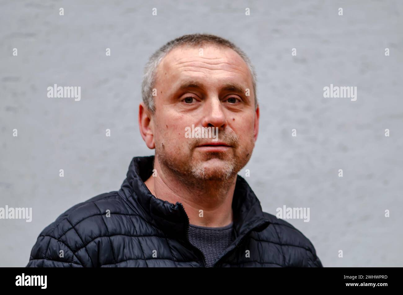 A gray-haired elderly man 45-50 years old against a light-colored wall ...