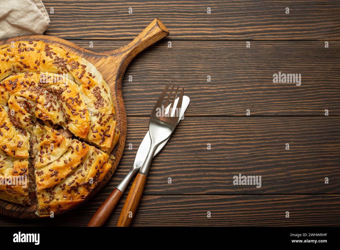Burek made of filo dough with filling on cutting board, dark brown ...