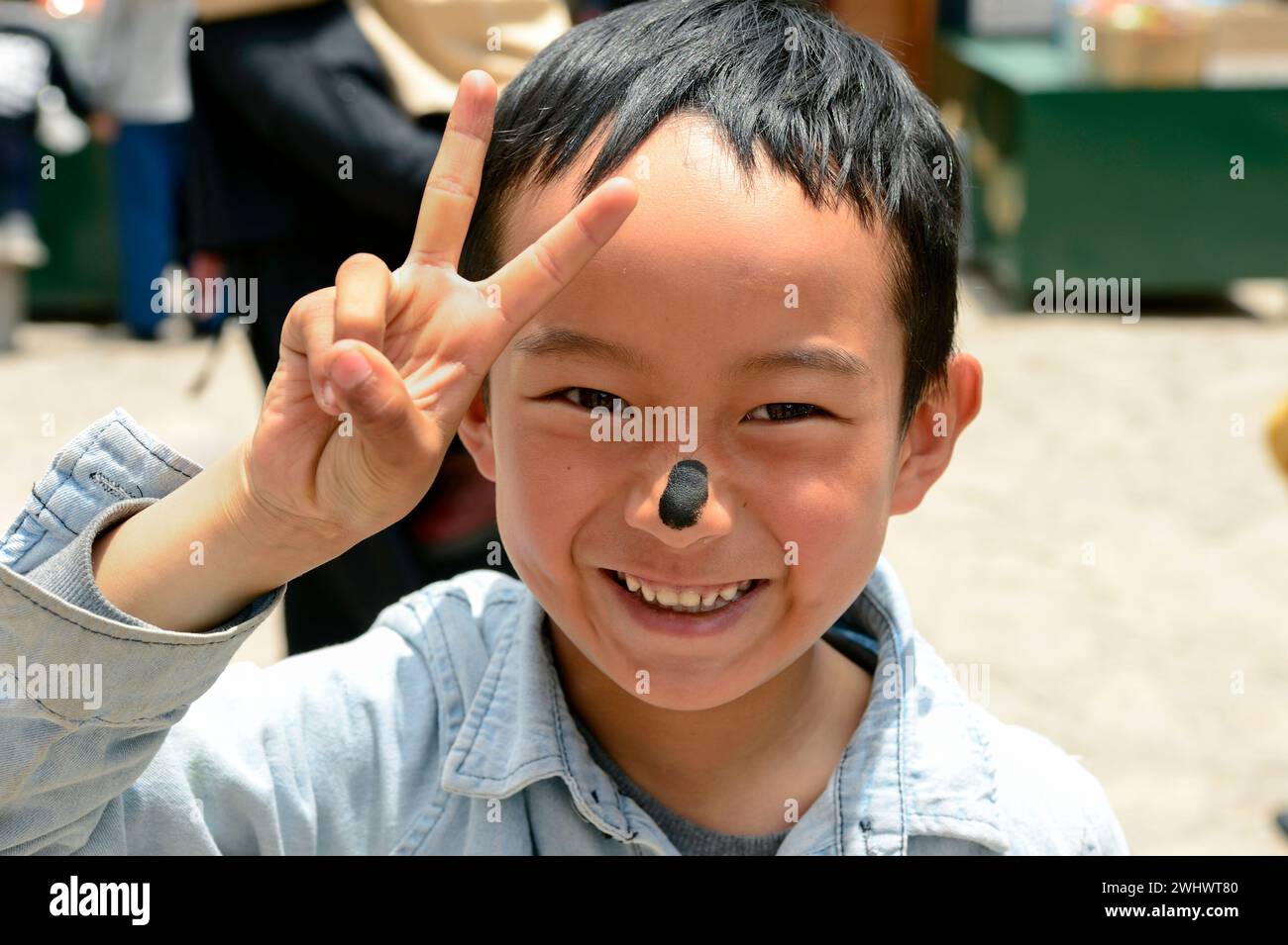 A Tibetan boy with a black nose flashes a peace sign in the main ...