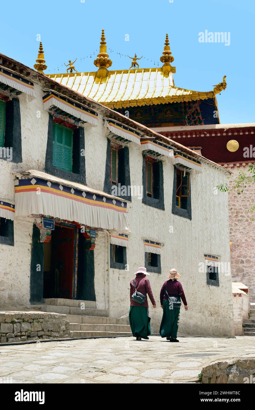 Two woman walk down a cobblestone street at Sera Monastery, located just outside Lhasa, Tibet ...