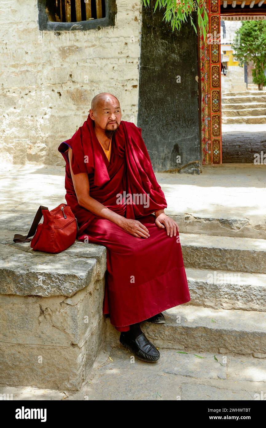 An elderly Buddhist monk rests on the stone steps at Sera Monastery in ...