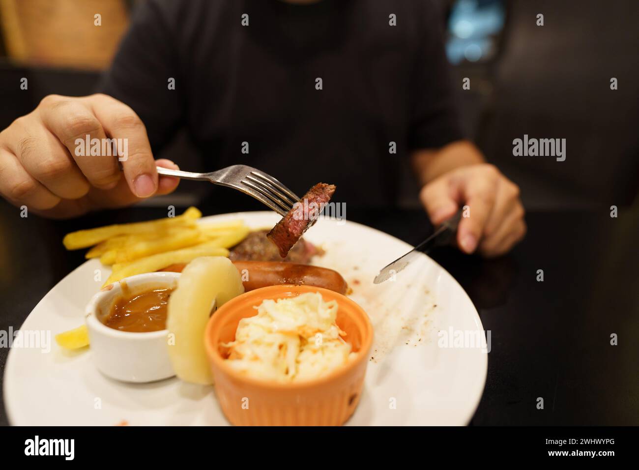Man eating Grilled Meats stake from plate. hand holding knife and fork ...