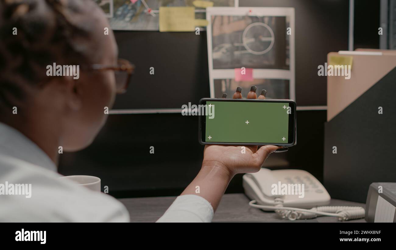 Police officer using greenscreen in evidence room, showing mockup ...