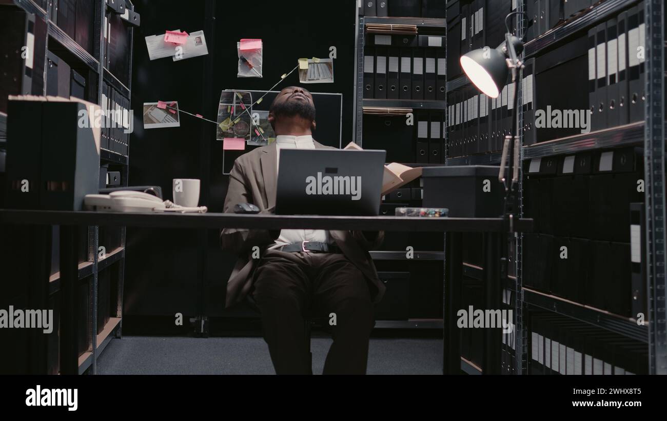 Male agent working with case information in evidence room, examining ...
