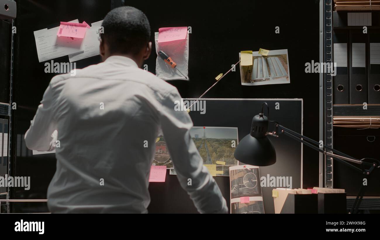 Male inspector analyzing evidence on board in archive room, reading ...