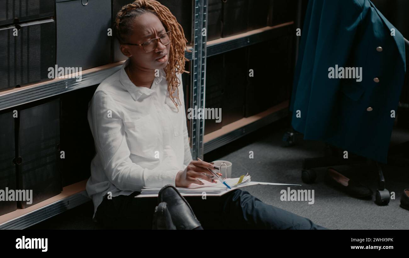 Police archive colleagues reading case information sitting on the floor ...