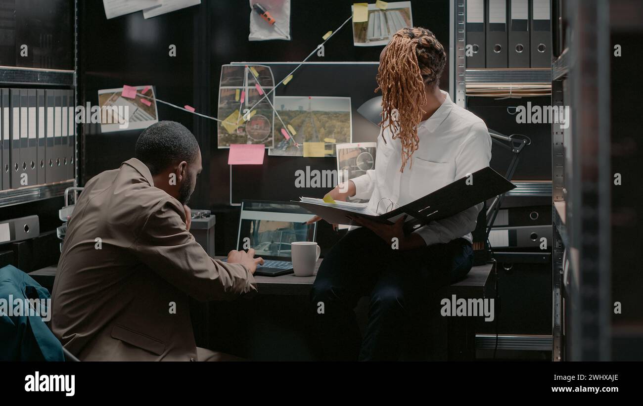 Two police officers looking at detective evidence map, investigators ...