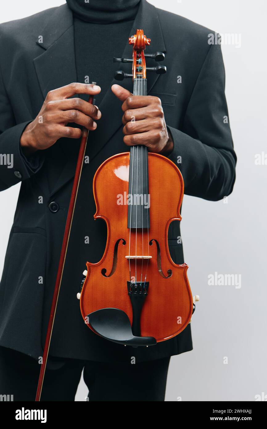 Elegant African American man in black suit holding a violin on a white ...