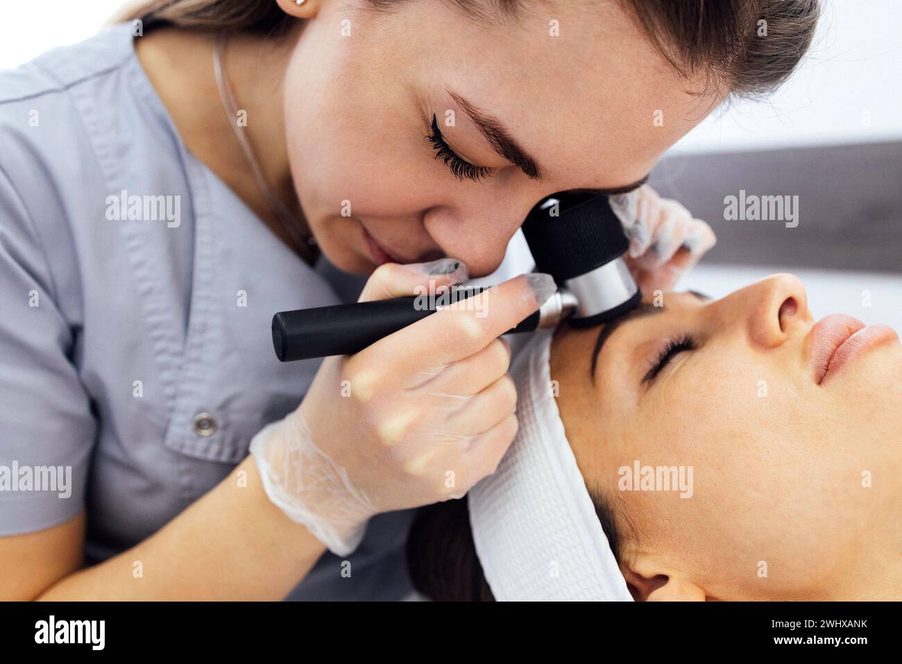 Doctor dermatologist examines skin of client face of beauty salon with ...