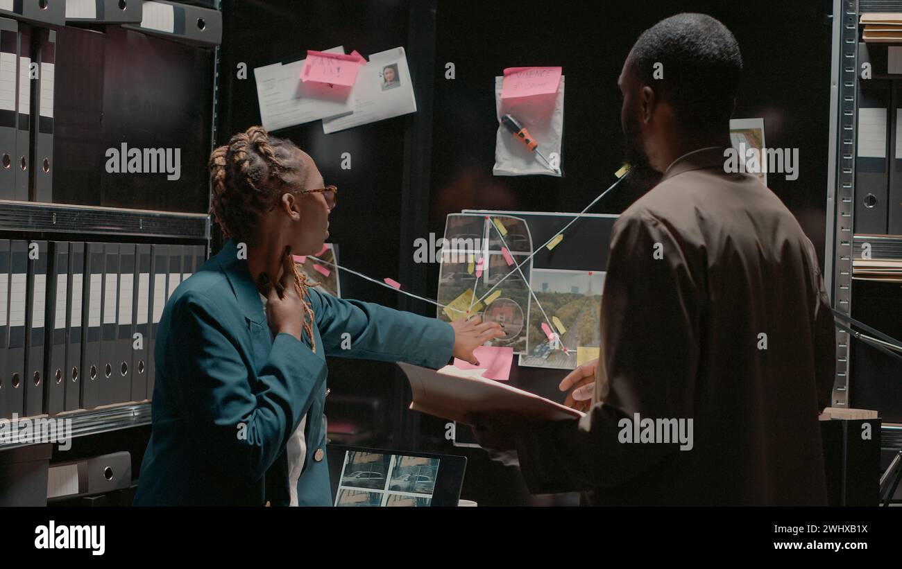 Detective partners analyzing criminal records in office, looking at ...