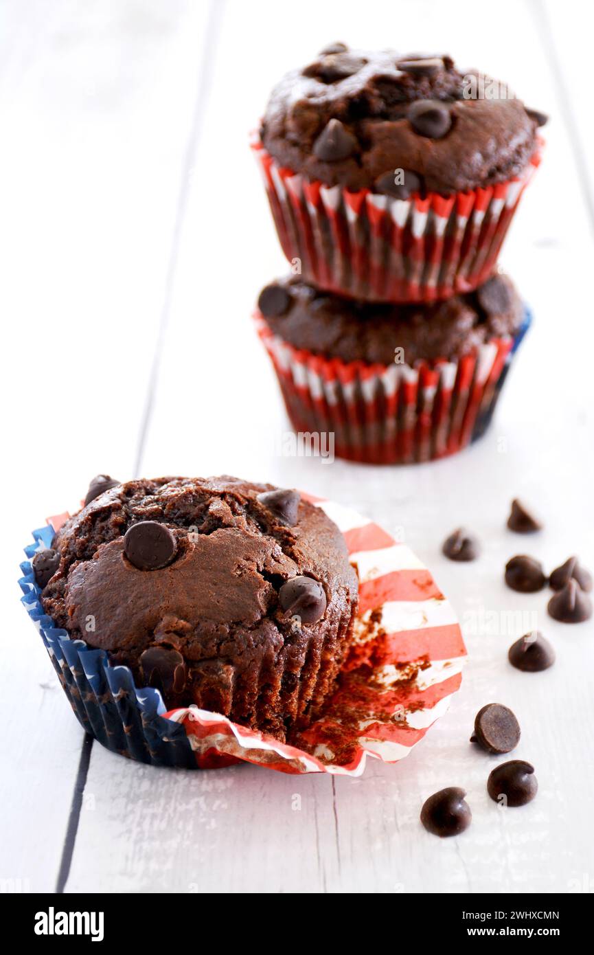 Double chocolate muffins stacked and paper liner opened on rustic ...