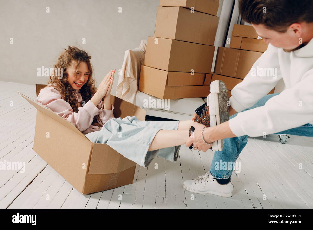 Happy young family couple man pull woman inside box. Moving with ...