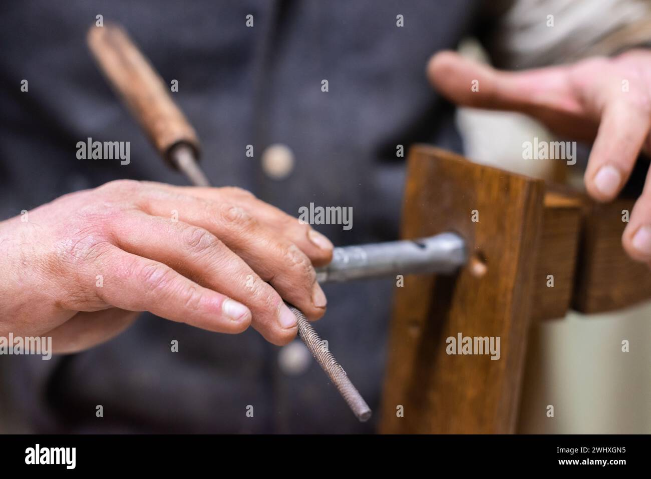 The carpenter screws in the bolt using a cylindrical wrench and a file ...
