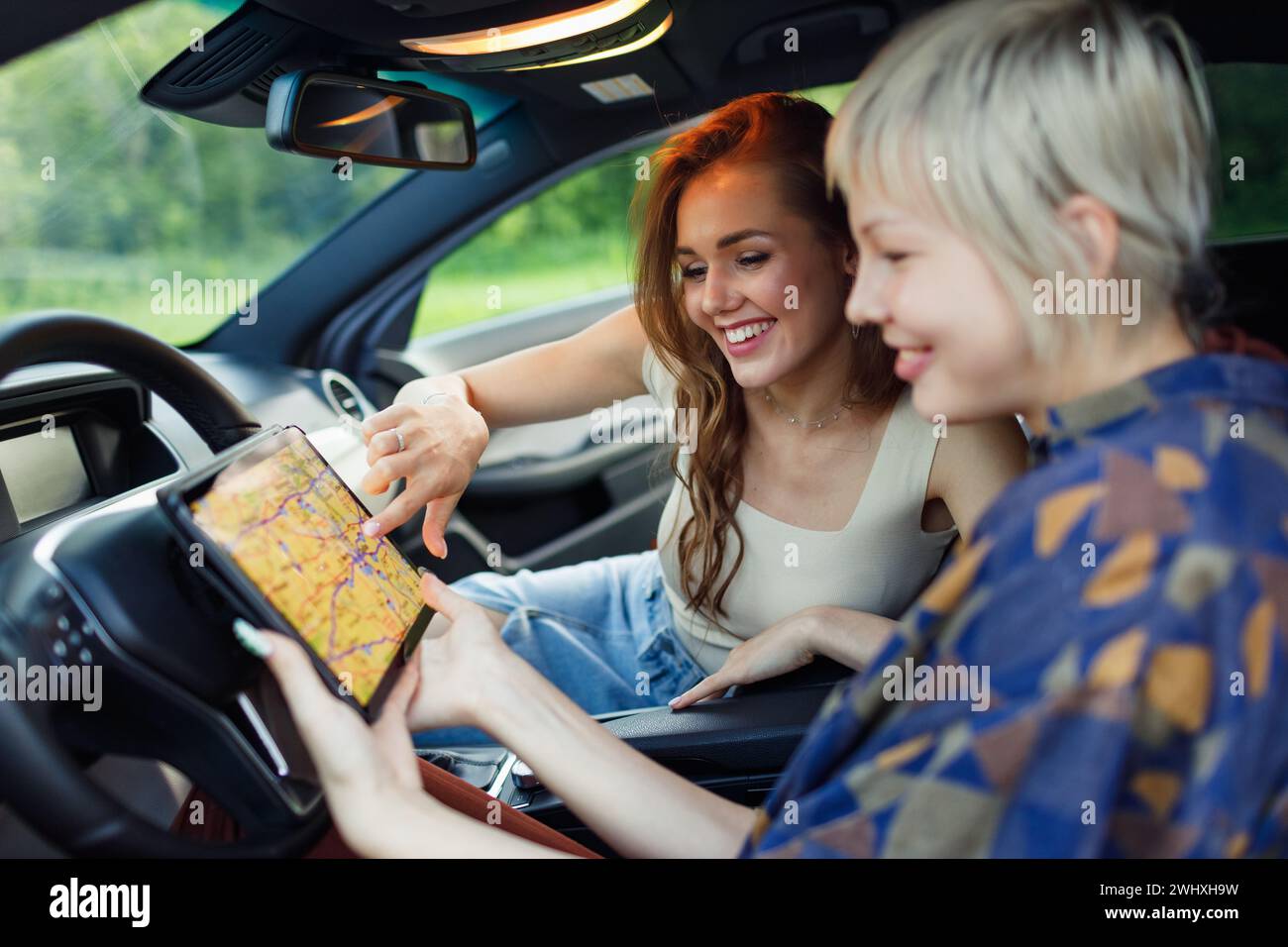 Happy young two women driver tourist travelers with digital tablet pad ... Happy young two women driver tourist travelers with digital tablet pad ...